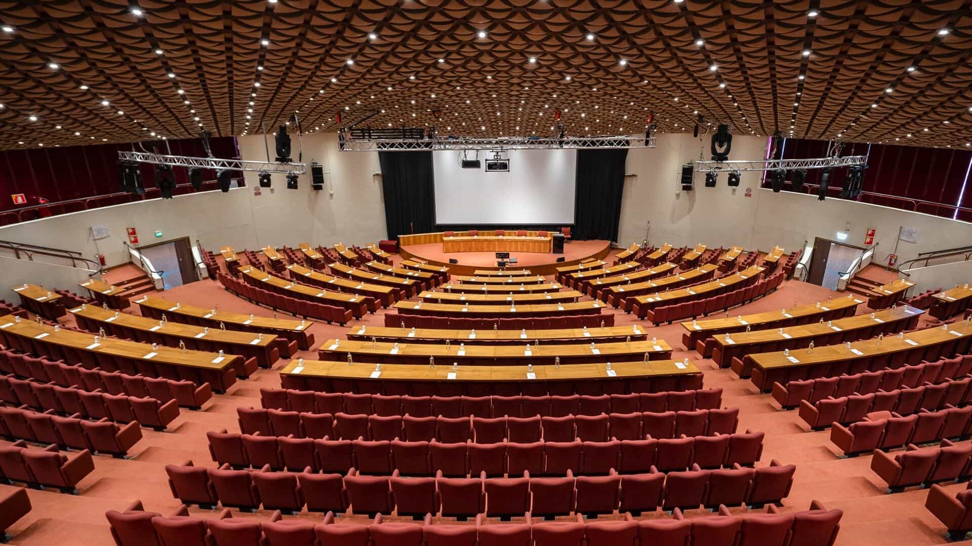 Un auditorium del Palazzo dei Congressi con file di poltrone rosse e ...
